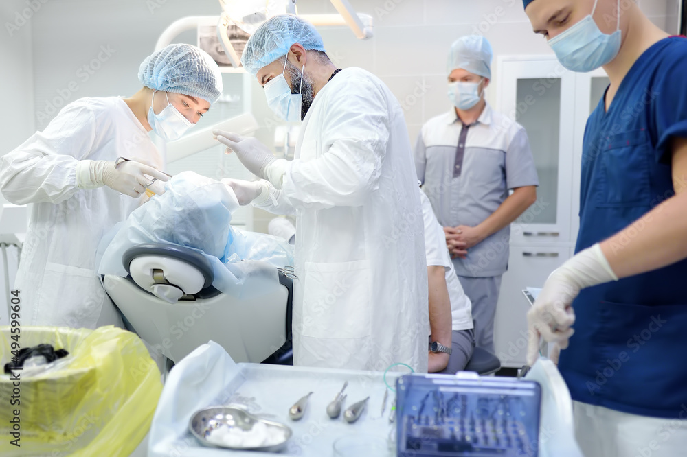Surgeon and nurse during a dental operation.Anesthetized patient in the ...