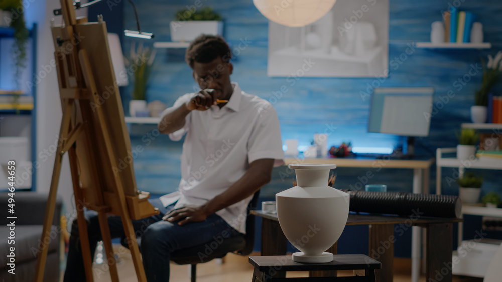 Black young man drawing vase for creative project in artwork space ...