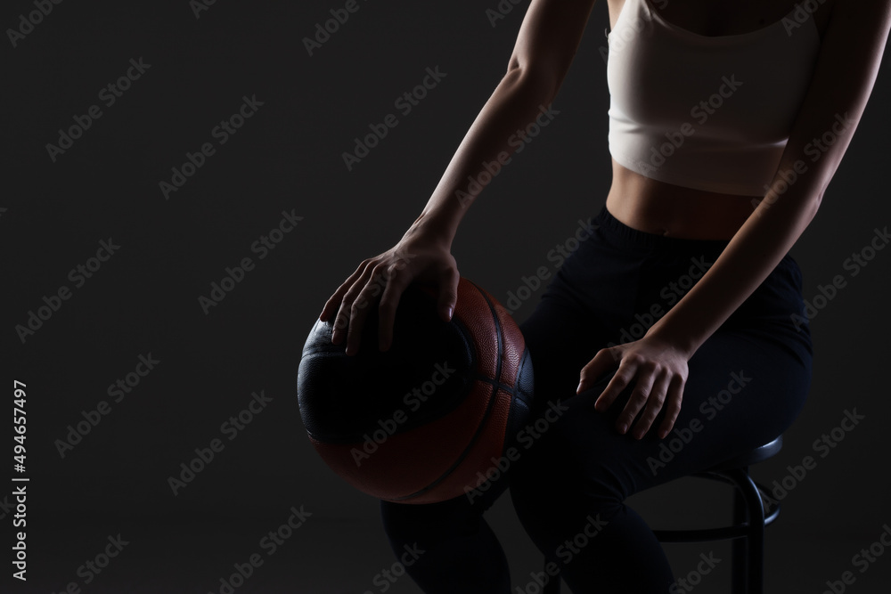 Teenage girl with basketball. Side lit studio portrait against dark ...