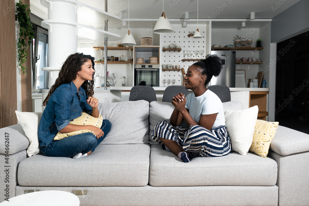 Two young friends and roommates sitting on sofa in their modern cozy ...