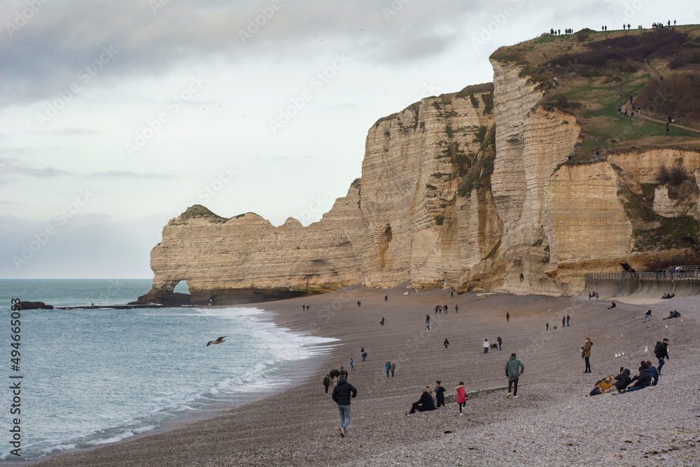 Falaises d'Etretat et minuscules touristes à leur pied. Plage de galet ...