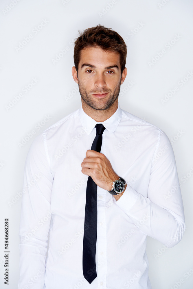 Adjusting his tie. Handsome young guy adjusting his tie against a white background. Stock Photo ...