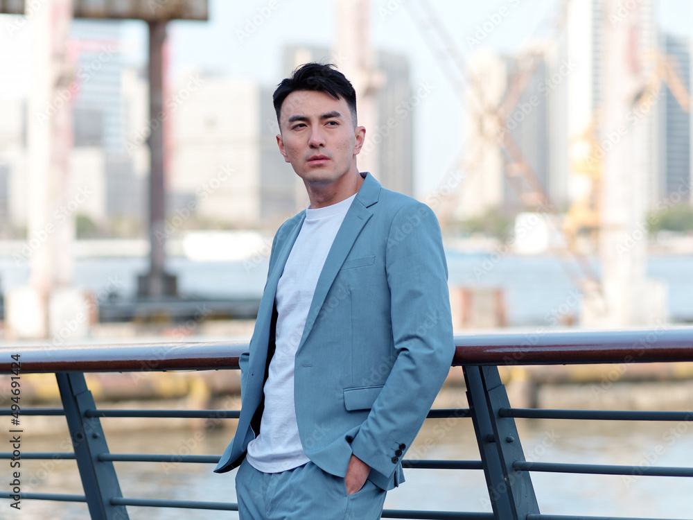 Portrait of handsome Chinese young man in light blue suit and white ...