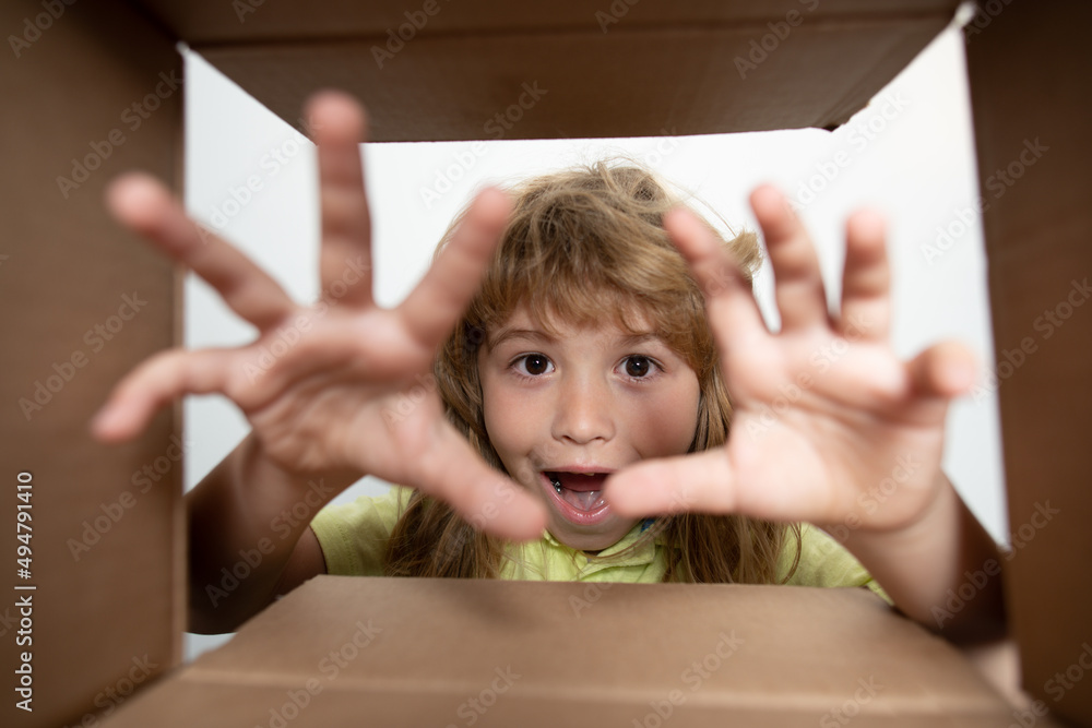 Child opens carton box and pulling out gift from it, take by hand gift ...