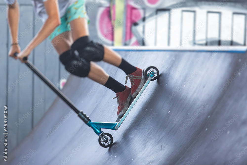 Skate park view with kids on a kick scooter doing tricks and stunts ...