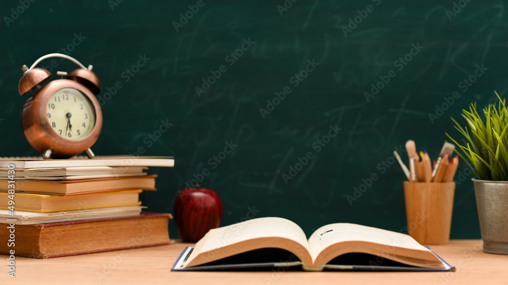 Open textbook on study table with stack of books and decor against ...
