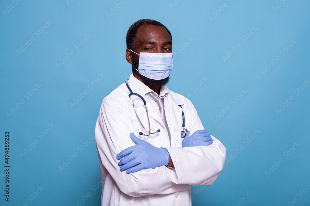 Portrait of confident doctor wearing scrubs with face mask and latex ...