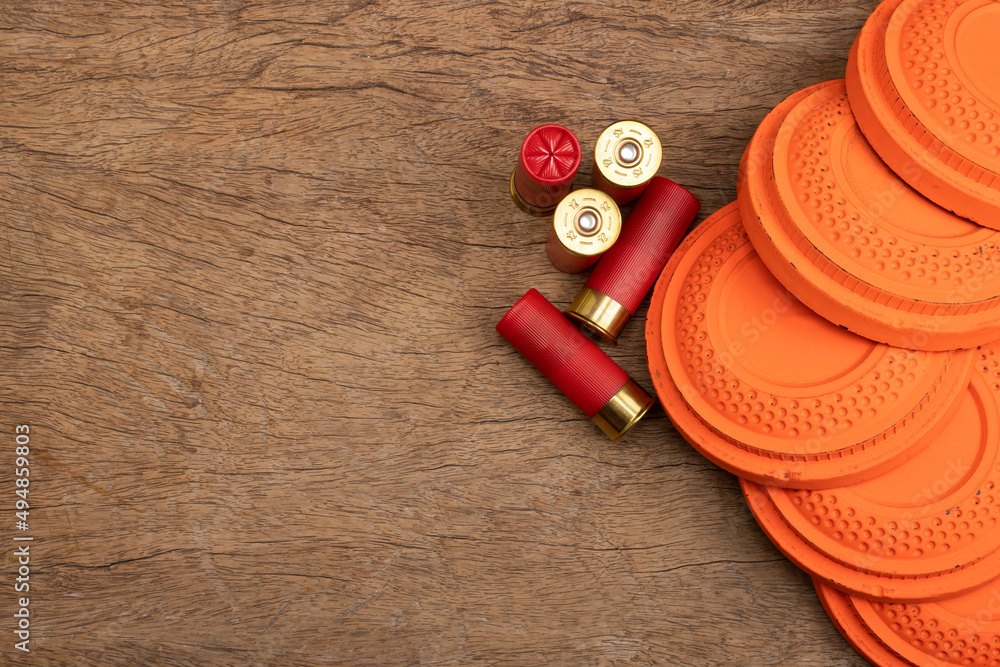 Flying clay pigeon target with shot gun bullet shell on wooden ...