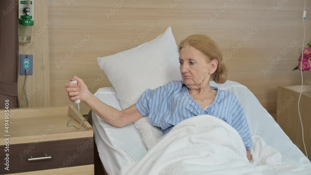 Elderly female patient pushing emergency nurse call button on the bed ...