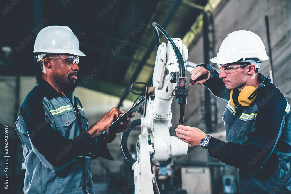 Factory workers working with adept robotic arm in a workshop . Industry ...