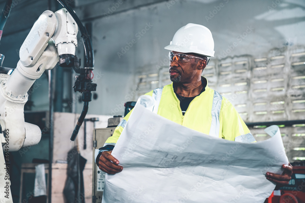 African American factory worker working with adept robotic arm in a ...