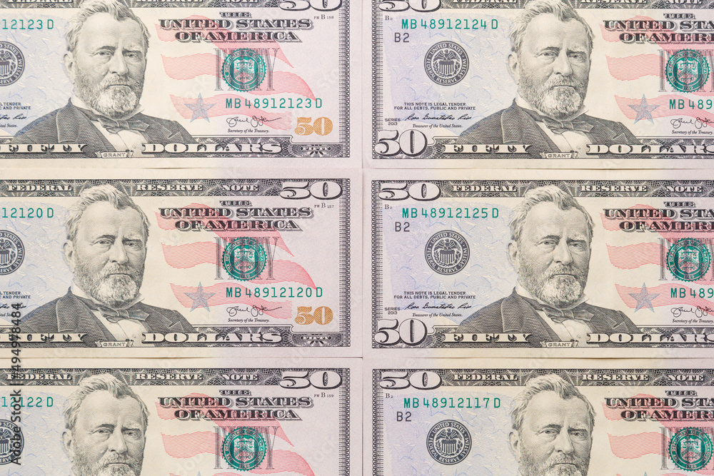 Fifty dollar bills are laid out in a row on a flat surface. Stock Photo | Adobe Stock