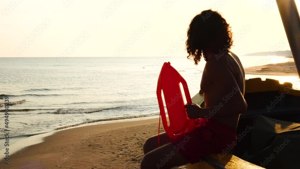 Lifeguard with orange rescue buoy is standing on the watch, at the ...