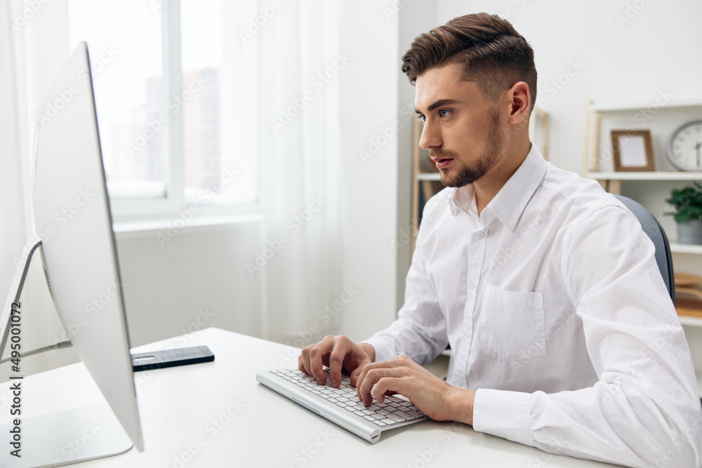 handsome businessman sitting at a desk in front of a computer with a ...