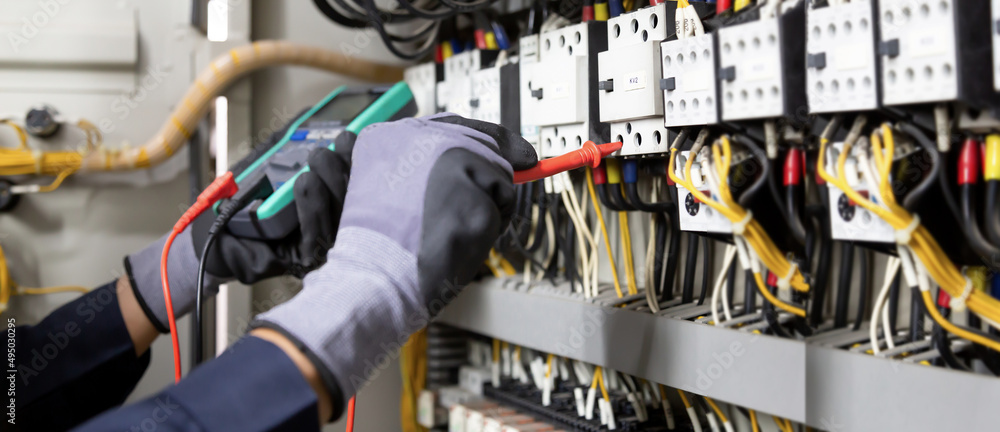 Electrician engineer tests electrical installations and wires on relay ...