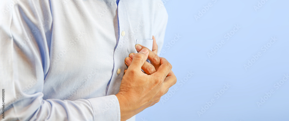 Hand squeezing the left chest pain on blue background concept of heart ...