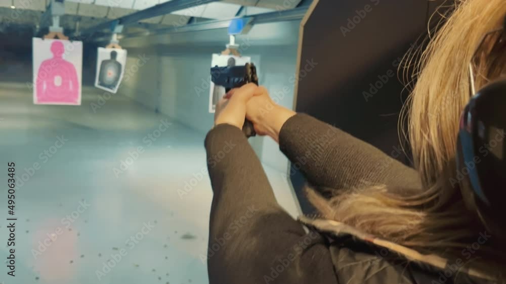Woman shooting at a target with a pistol in a shooting range. Woman ...