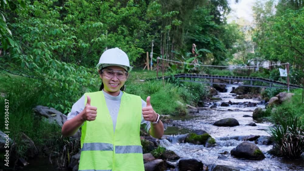 Environmental engineer wearing a helmet makes a thumbs-up gesture and ...