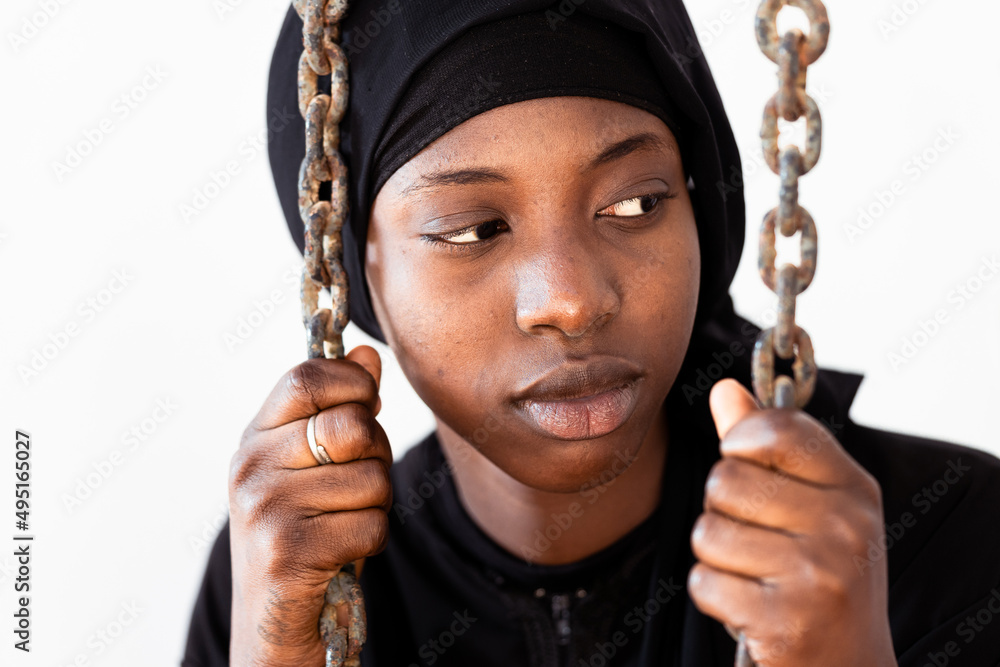 Sad young African girl behind the chains, symbolizing captivity ...