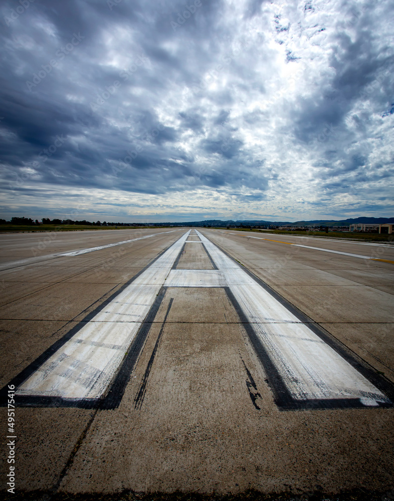 Airport runway landing and take off marks with clouds in the distance ...