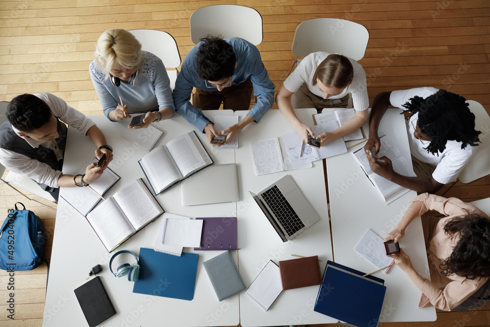 Overhead view group of multi ethnic students use smartphones sit at ...