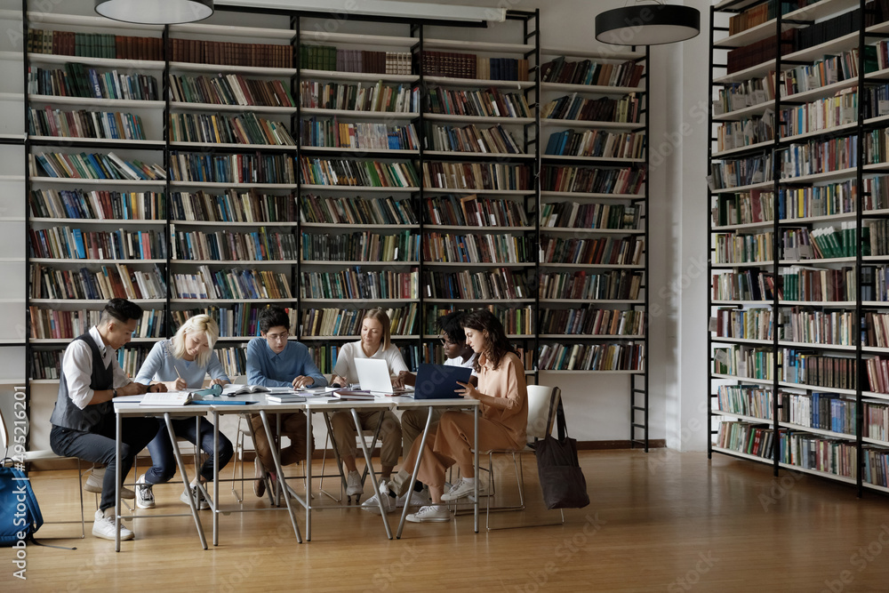 Foto de Group of multi racial students sit at table in spacious room of ...