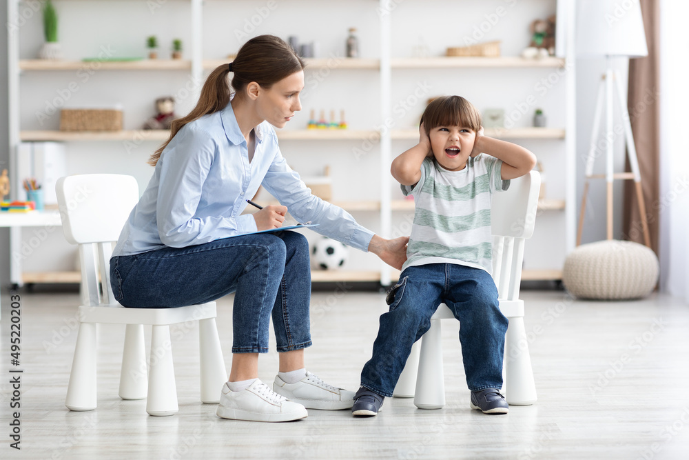 Emotional little boy screaming and covering ears during consultation at ...