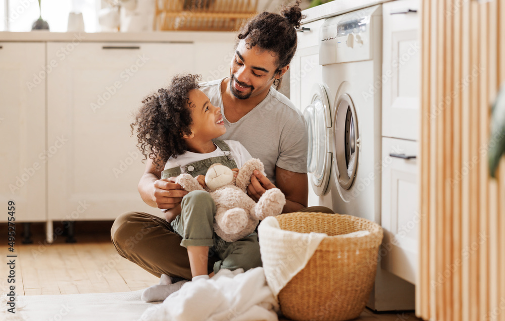 Son helping dad to load washing machine Stock Photo | Adobe Stock