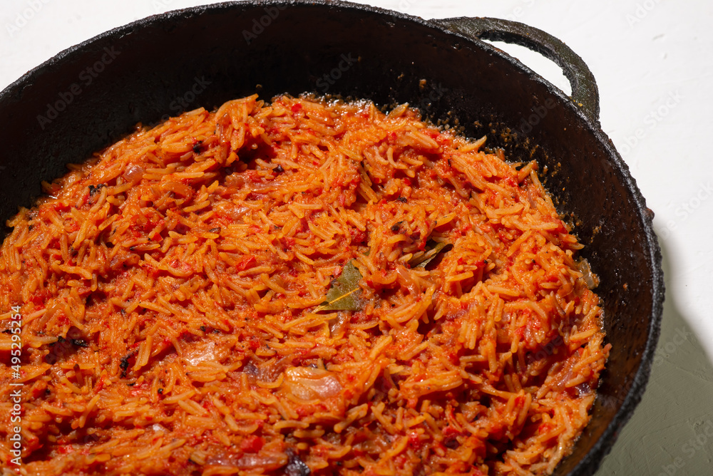 Jollof rice in a frying pan on a white background. A traditional ...