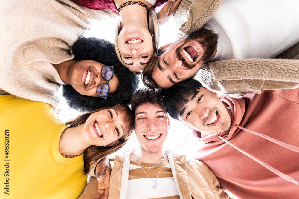 Multiracial group of friends standing in circle smiling at camera ...