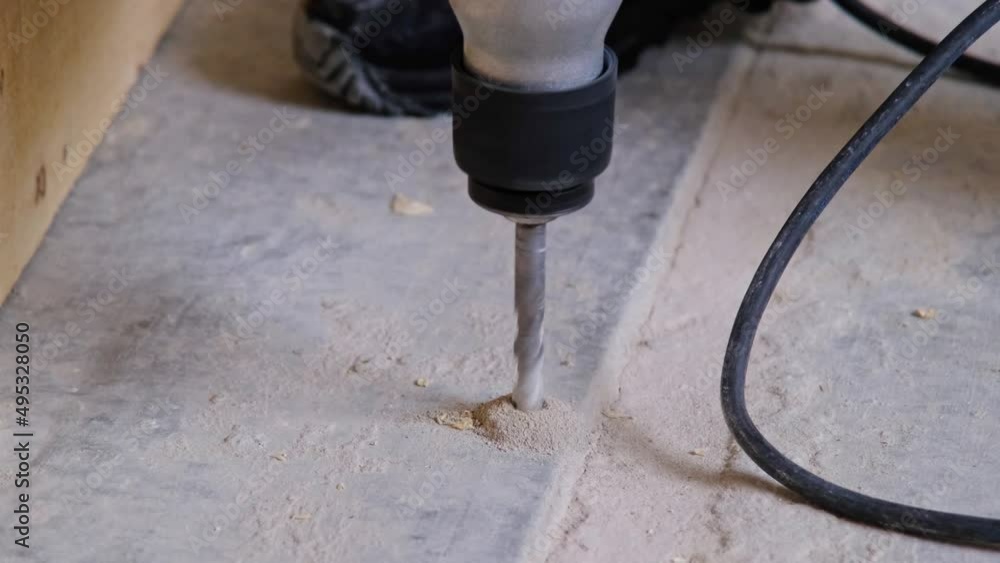 Drilling holes in the concrete floor of the house with a puncher drill ...