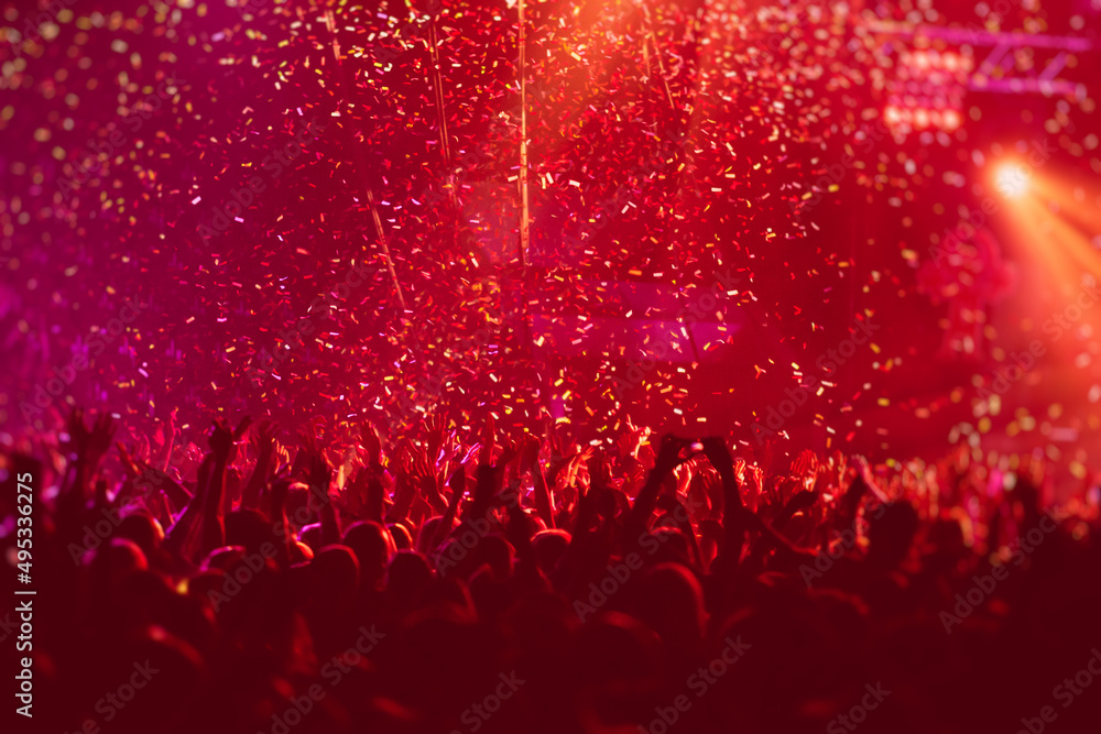 A crowded concert hall with scene stage in red lights, rock show ...