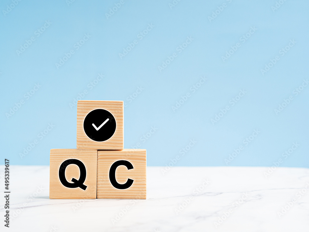 Wooden cubes with a checkmark symbol and letters Q and C on a marble ...