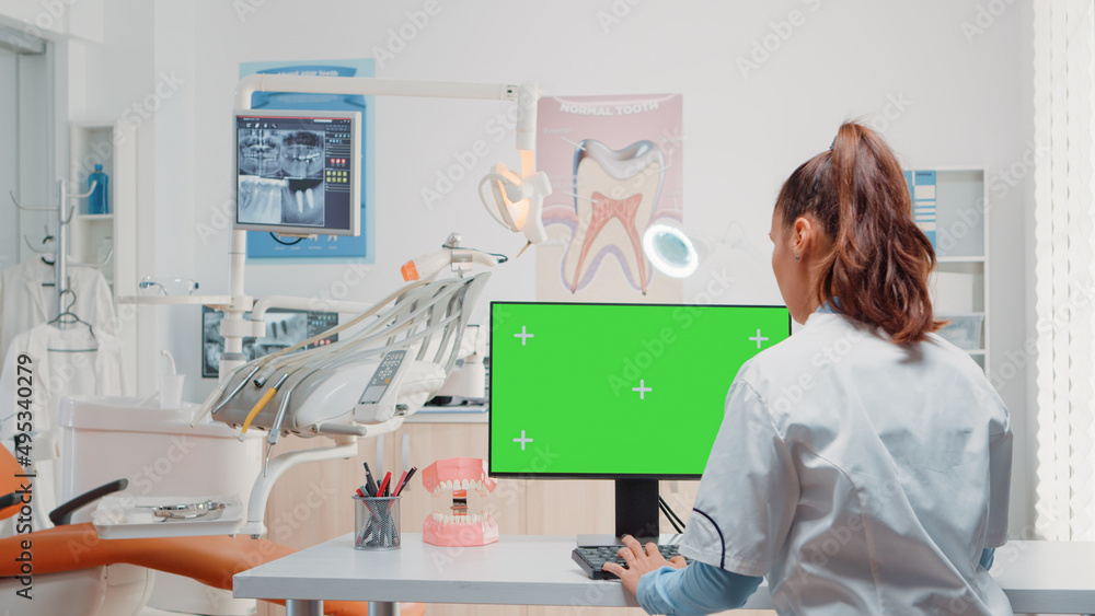 Dentist using computer with horizontal green screen on display ...