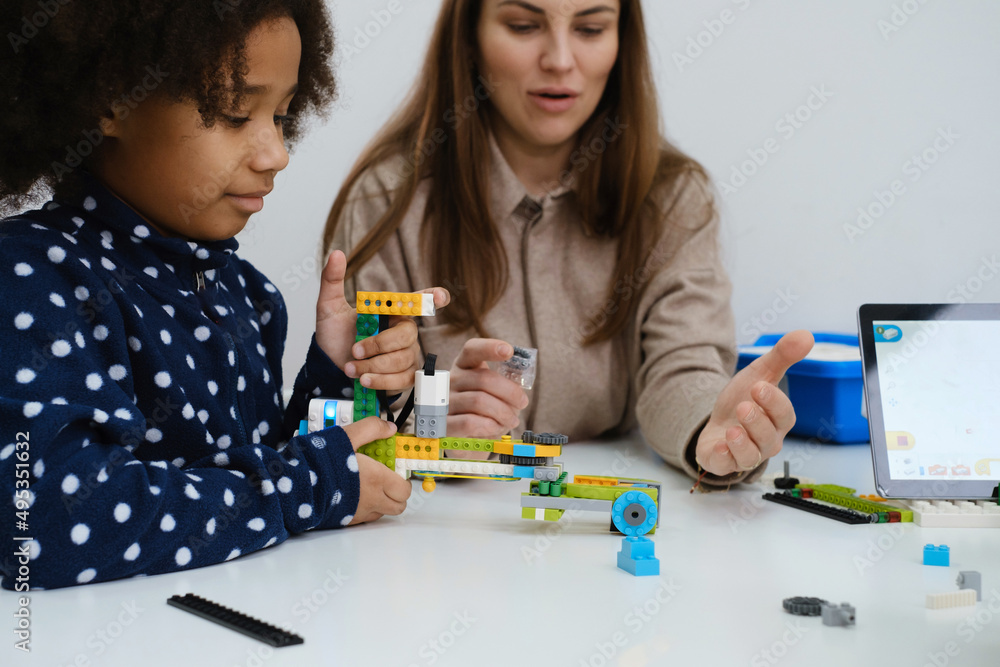 Multiethnic kids at STEM lesson constructing robot in classroom with ...