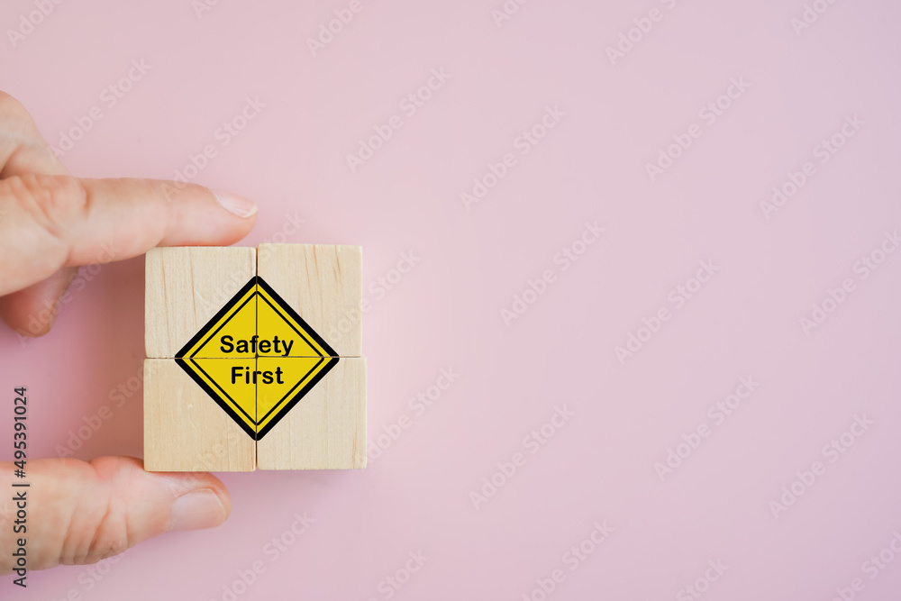 hand holds Safety first symbols icon on wooden cubes with pink ...