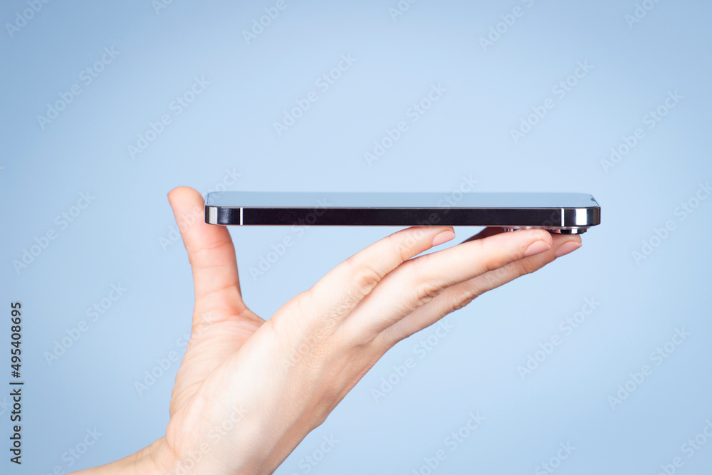 Woman hand holding smartphone screen face up side view on light blue ...