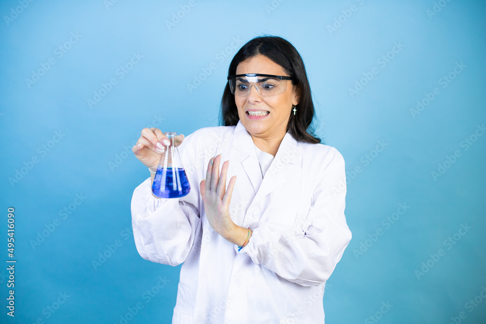 Young brunette woman wearing scientist uniform holding test tube over ...