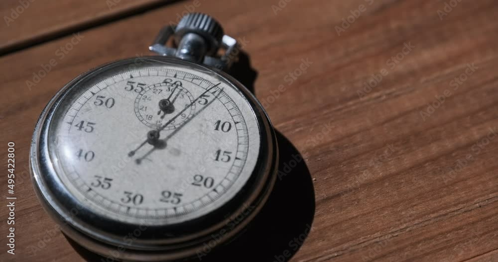 An antique stopwatch lies on wooden table and counts the seconds. Old ...