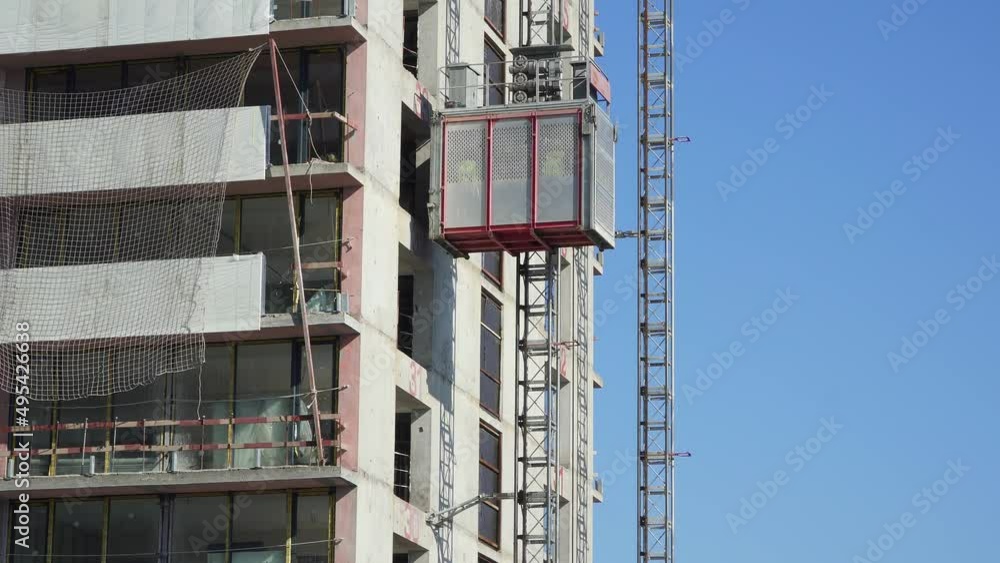 freight elevator at construction site of tall rides up and down. in ...