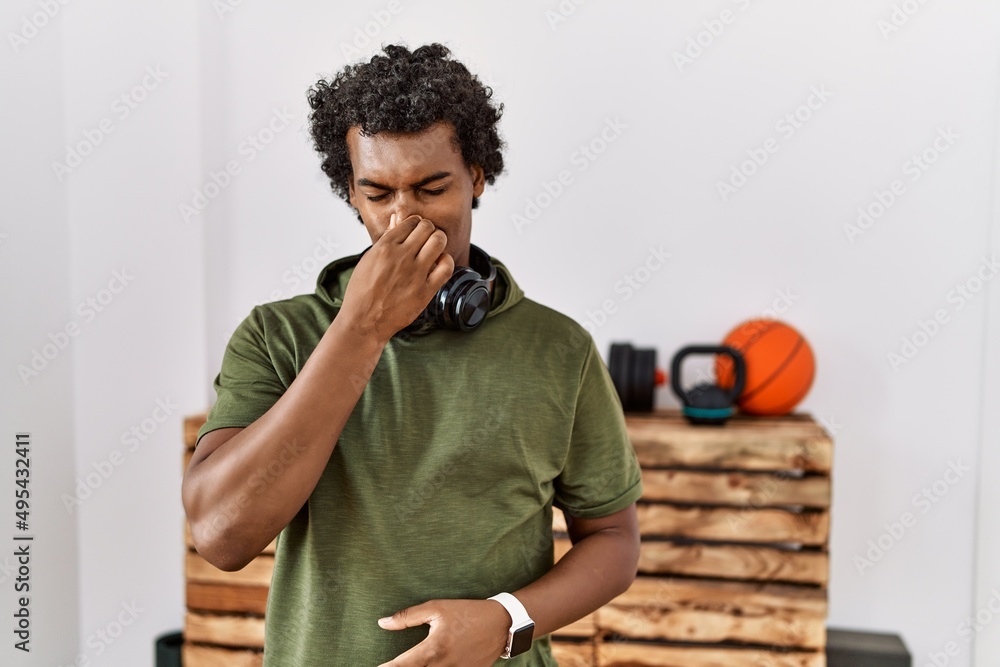 African man with curly hair wearing sportswear at the gym smelling ...