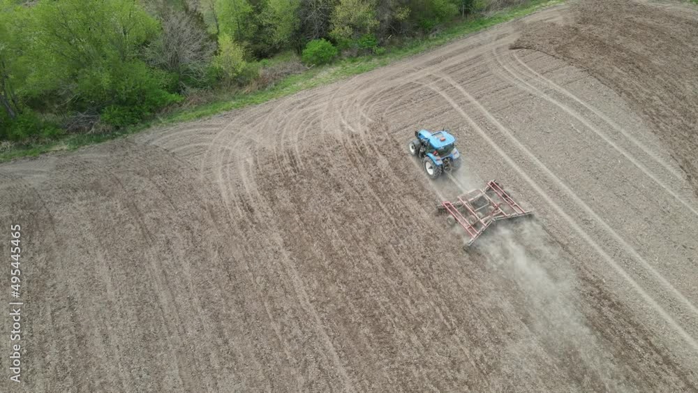 Bird eye view of farmer tilling dirt field in methodical rows. Slowly ...