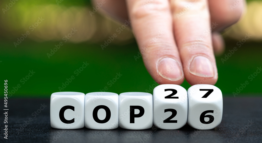 Symbol for the next climate change conference COP27. Hand turns dice ...