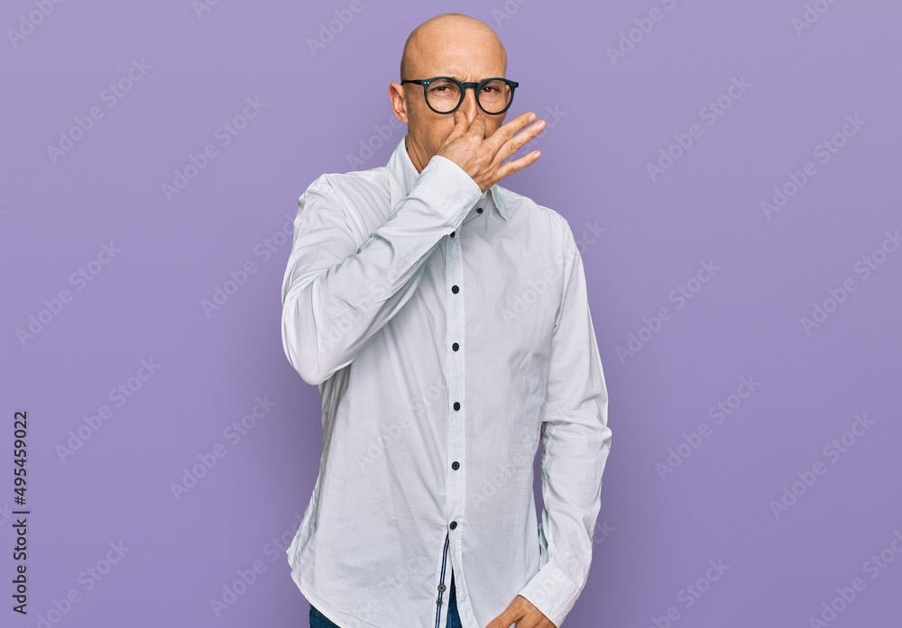 Bald man with beard wearing business shirt and glasses smelling ...