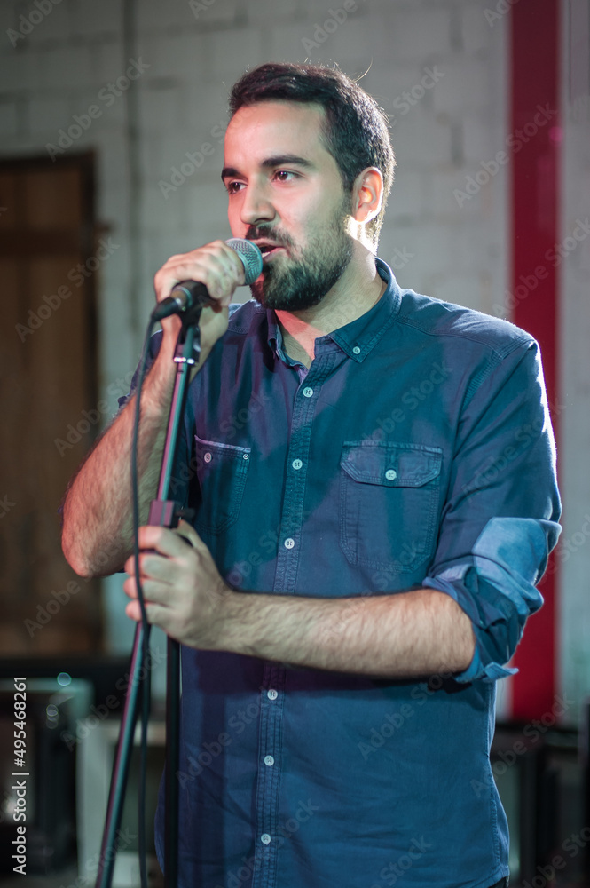 Smiling and witty stand up actor comedian on stage, talking and singing ...