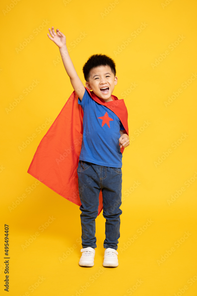 Smiling Superhero Asian boy in red cape isolated yellow background ...