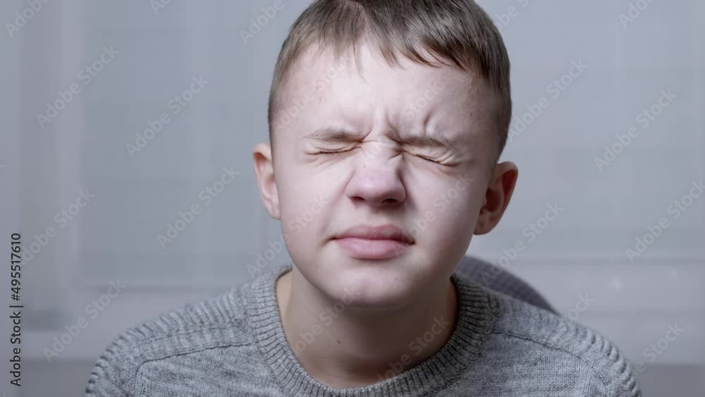 Smiling Boy Sitting in Room with his Eyes Closed and Squinting Hard ...