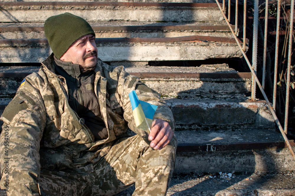Ukrainian military soldier in uniform with the flag of Ukraine. Symbol ...