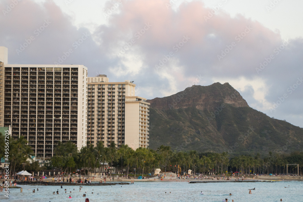 The sun sets on Honolulu, as seen from the lively beaches of Waikiki, a ...