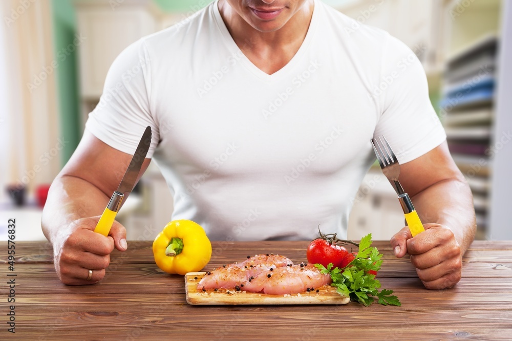 attractive handsome male eating health food salad and chicken at home ...